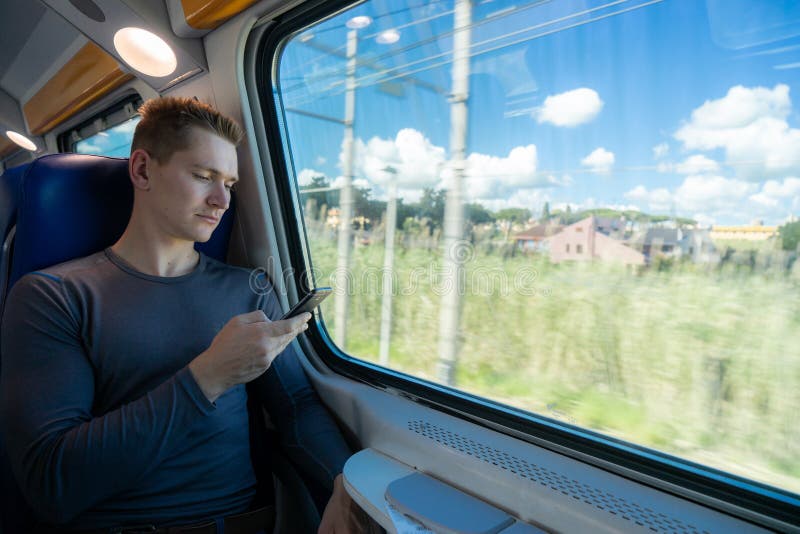 Young Man Commuting on Train Using Mobile Phone Stock Image - Image of ...