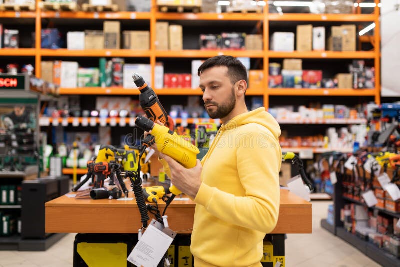 A Young Man Compares Two Drills in a Power Tool Store Stock Photo ...