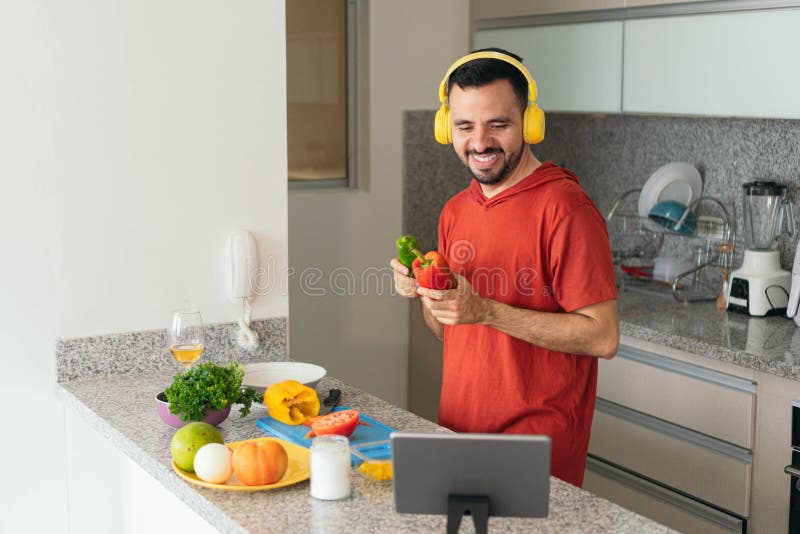 Young Man Cooking Lunch while Doing a Video Chat with His Tablet at ...