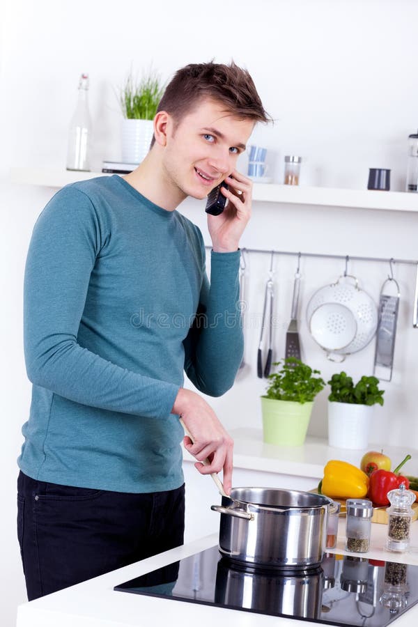 Young Man Cooking a Meal and Talking on the Phone in the Kitchen Stock ...
