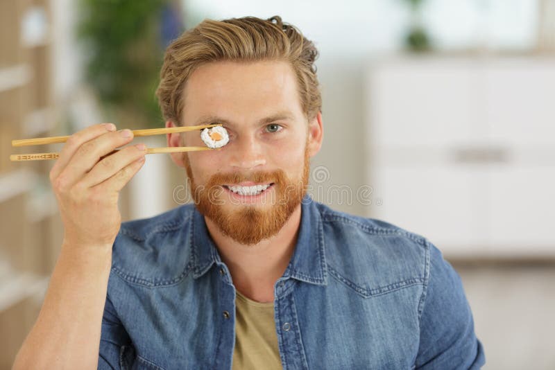 Young Man Covering Eye with Sushi Roll Stock Image - Image of kitchen ...
