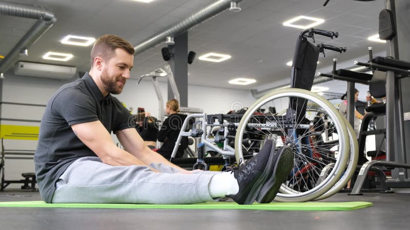 A Young Man with Disabilities Does Mobility Exercises in the Gym. Stock ...