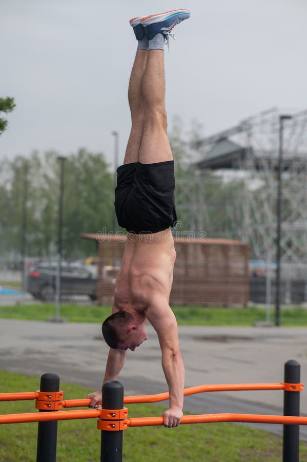 A Young Man Doing a Handstand on Parallel Bars Outdoors. Workout. Stock ...