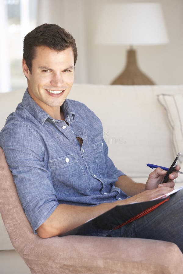 Young Man Doing Paperwork and Using Mobile Phone at Home Stock Photo ...