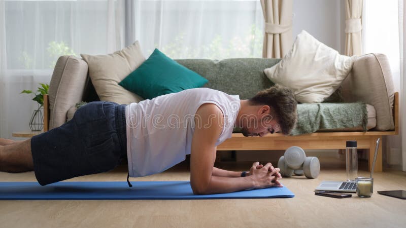 Young Man Doing Plank Exercise and Watching Online Tutorial on Computer ...