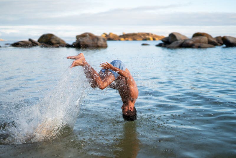 Young Caucasian Man Doing a Somersault in the Beach Inside the Water ...