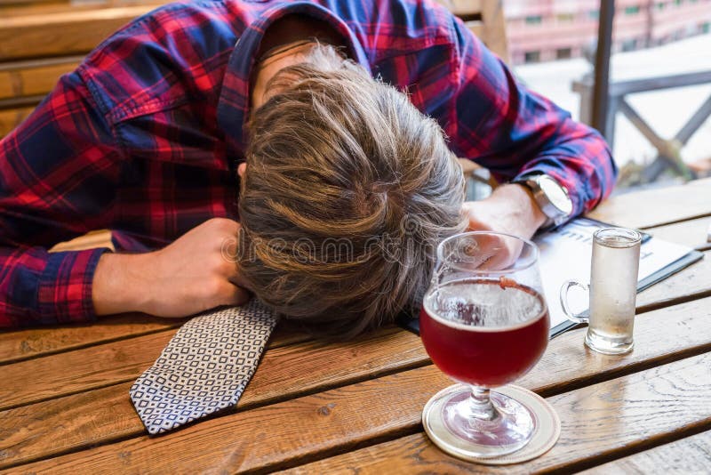 Young Man Drinking Alcoholic Lying or Sleeping on the Table in the Bar ...