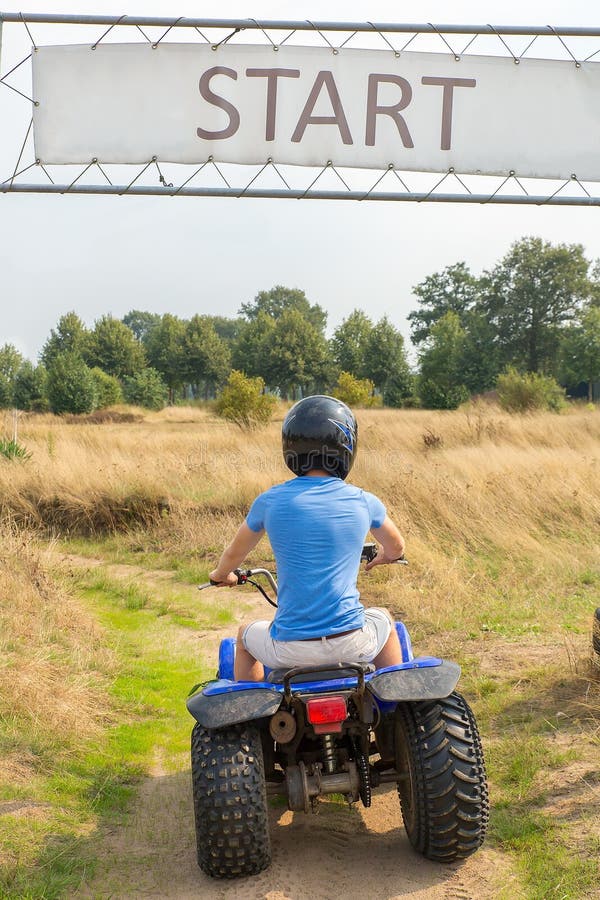 Young Man Driving Quad with Start Banner Stock Image - Image of cross ...