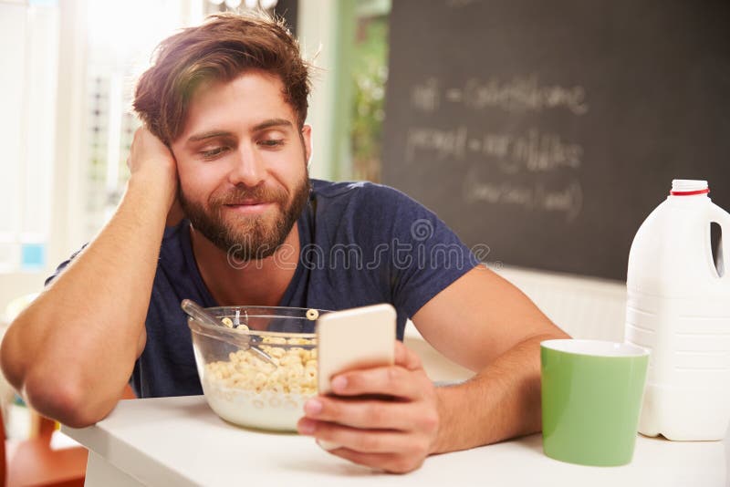 Young Man Eating Breakfast Whilst Using Mobile Phone Stock Image ...