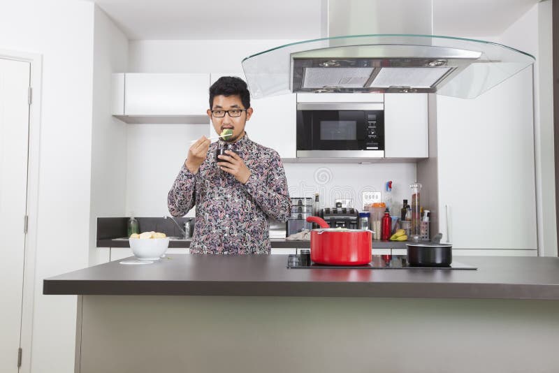 Young Man Eating Broccoli at Kitchen Counter in Home Stock Photo ...