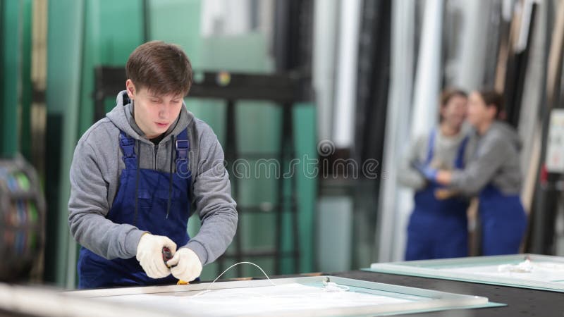 Young Man Employee in Blue Overall Measures Given Length of Plastic ...