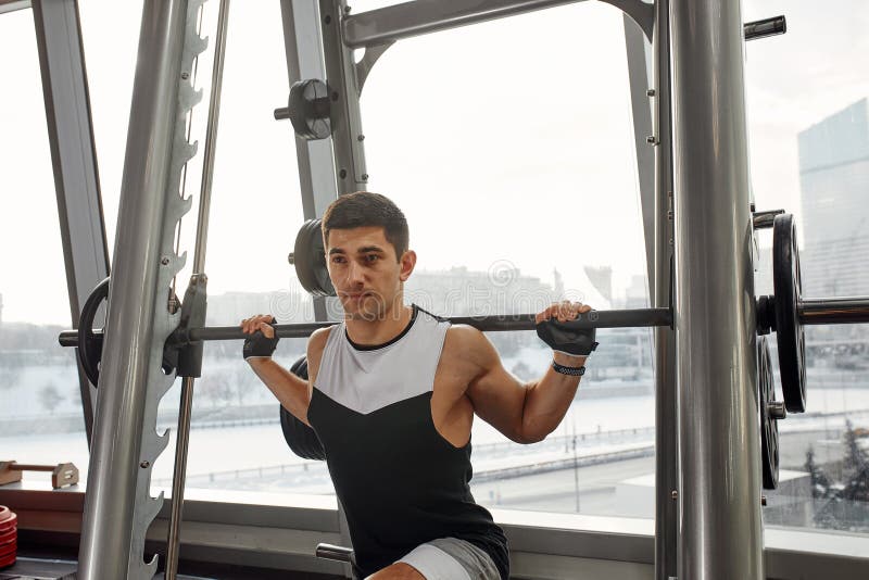 Young Man is Engaged on a Modern Simulator in the Gym. Male Athlete is ...