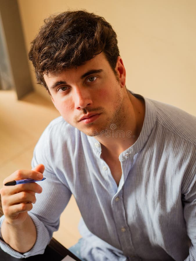 Young Man Engaged in Thoughtful Reflection while Writing in a Casual ...