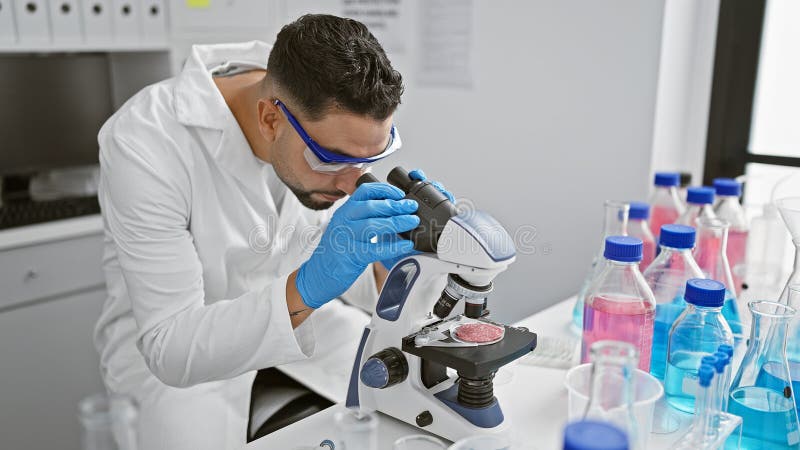 A Young Man Examines a Specimen Under a Microscope in a Laboratory ...