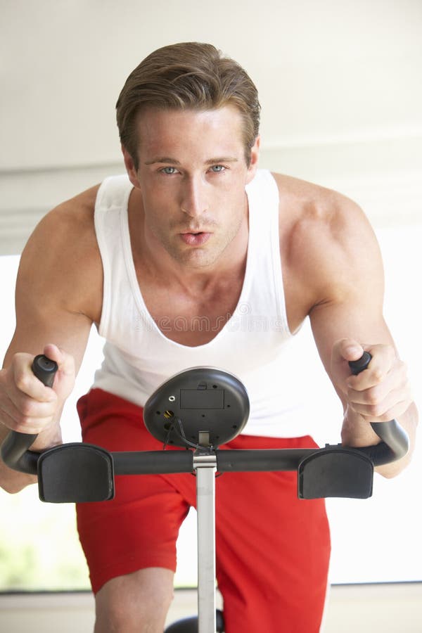 Young Man on Exercise Bike stock image. Image of exercising - 54943537