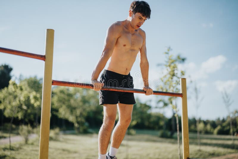 Young Man Exercising on Outdoor Parallel Bars in a Park during a Sunny ...