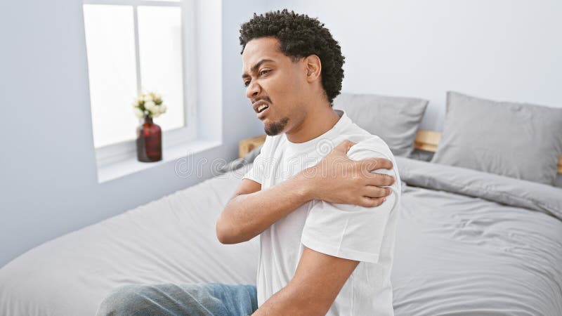 A Young Man Expressing Discomfort while Holding His Shoulder in a ...