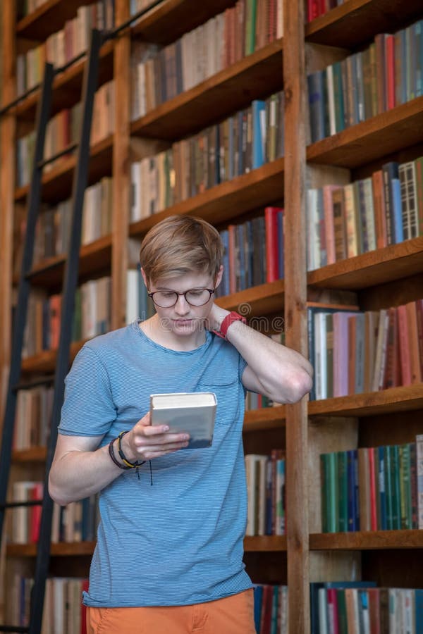 Young Man in Eyewear Reading a Book and Looking Interested Stock Image ...