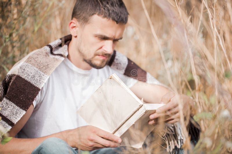 A Young Man on the Field Reading a Book Stock Photo - Image of field ...