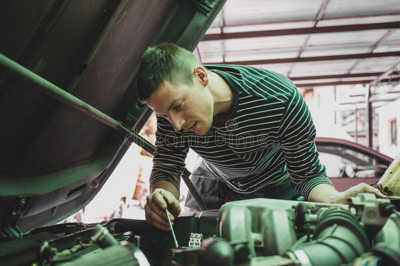 Young Man Fixing an Engine of a Car, Using a Wrench and Looking into ...