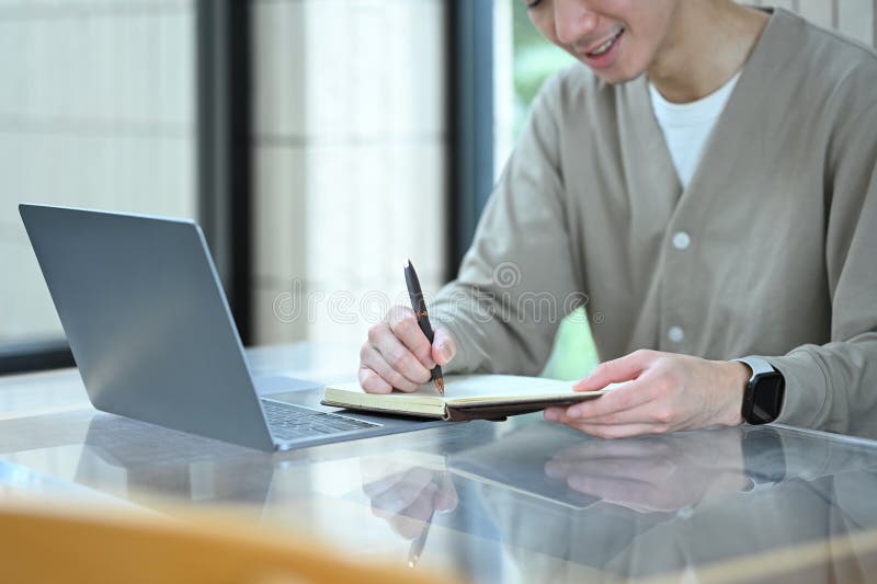 Young Man Freelancer Using Laptop and Writing Note or Checking Working ...