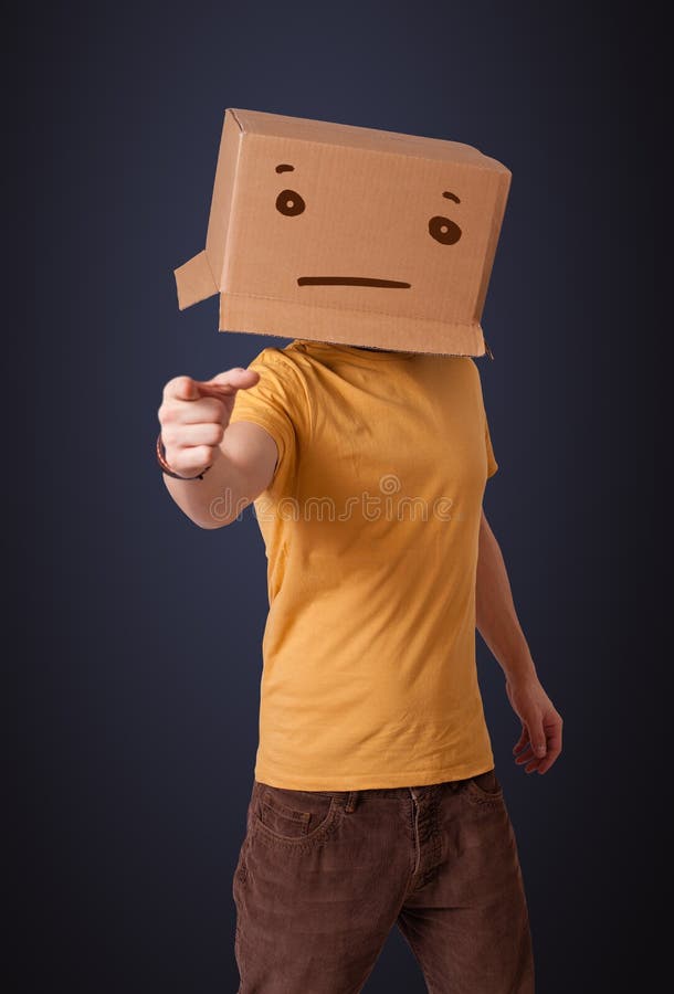 Young Man Gesturing with a Cardboard Box on His Head with Straight Face ...