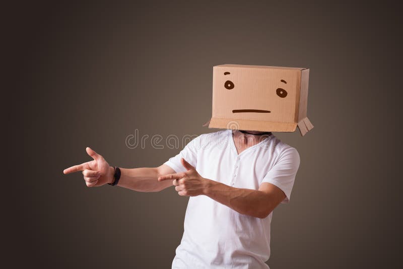 Young Man Gesturing with a Cardboard Box on His Head with Straight Face ...