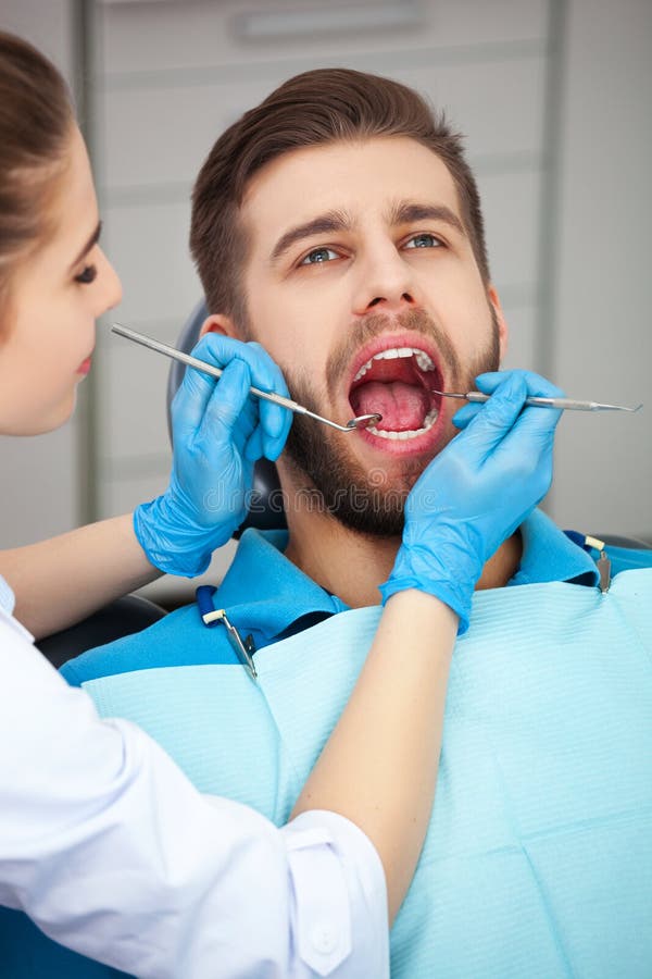 Young Man Getting His Teeth Checked by a Dentist. Stock Image - Image ...