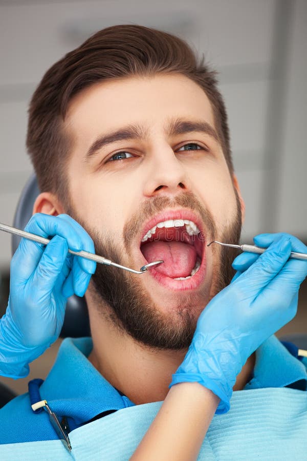 Young Man Getting His Teeth Checked by a Dentist. Stock Photo - Image ...