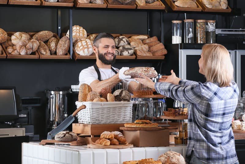 Young Man Giving Fresh Bread To Woman in Bakery Stock Photo - Image of ...