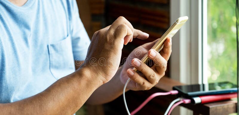 Young Man Hands Holding and Playing Smartphone while Charging the ...
