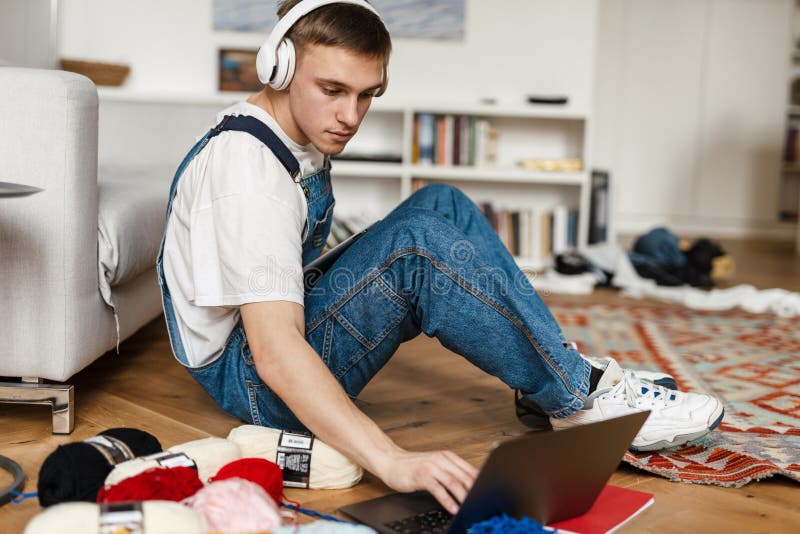 Young Man in Headphones Using Computer while Working on Craft Rug Stock ...