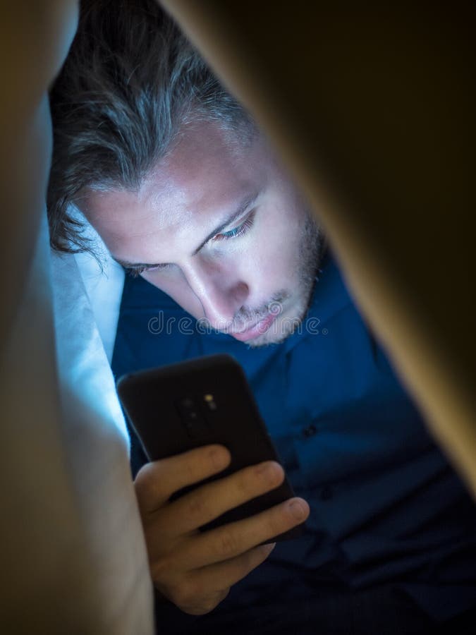 Young Man Hiding while Using a Mobile Phone Stock Photo - Image of ...