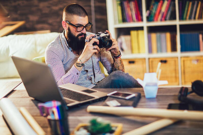 Man Holding Camera and Sitting by Table with Computer at Home Office ...