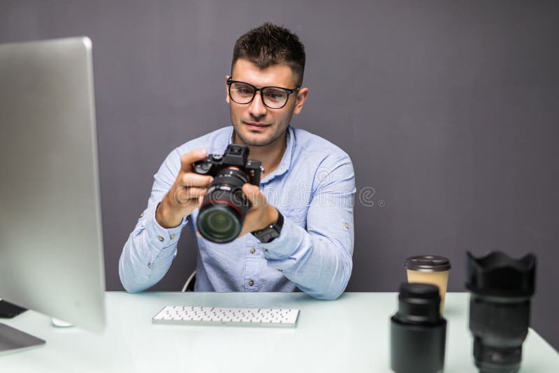 Young Man Holding Digital Camera and Smiling while Sitting at His ...