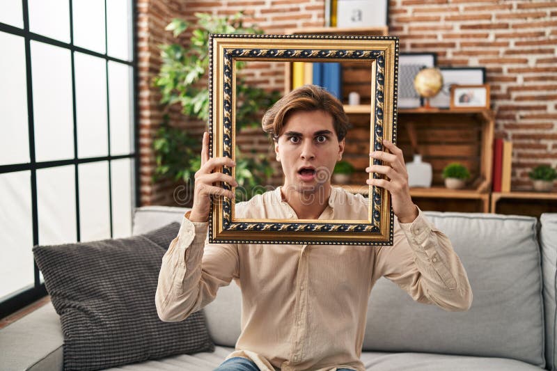 Young Man Holding Empty Frame in Shock Face, Looking Skeptical and ...