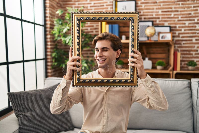 Young Man Holding Empty Frame Winking Looking at the Camera with ...