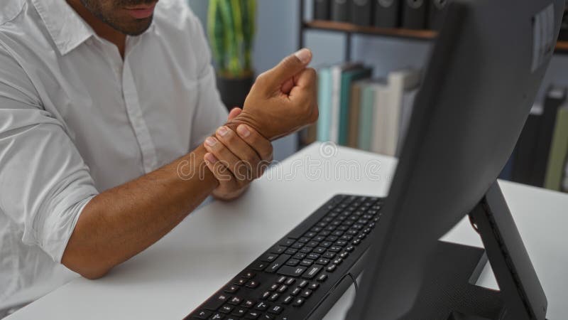 Young Man Holding His Wrist while Sitting at an Office Desk in a ...
