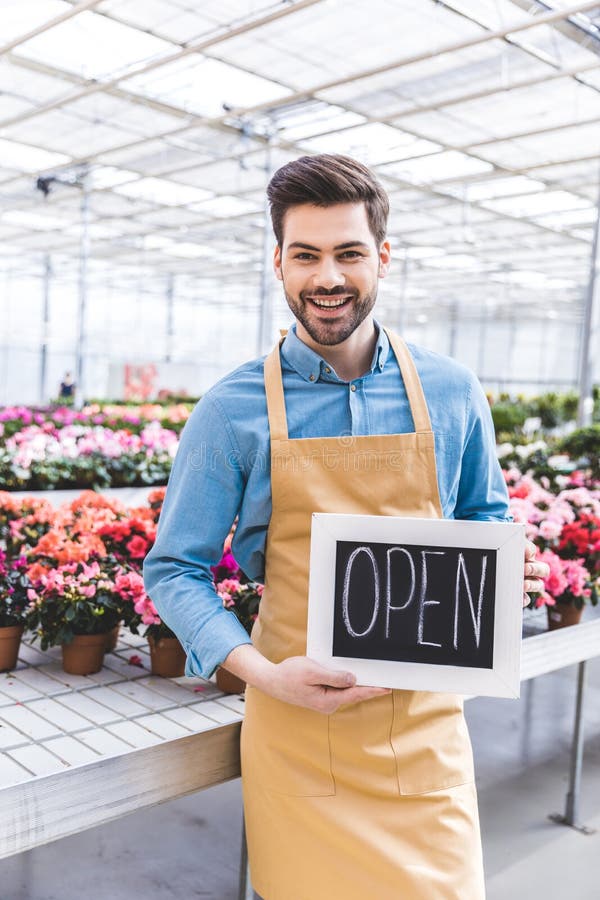 Young Man Holding Open Board by Flowers Stock Image - Image of handsome ...