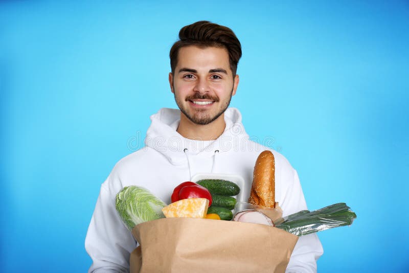 Young Man Holding Paper Bag with Products on Color Background. Food ... Young Man Holding Paper Bag with Products on Color Background. Food ...