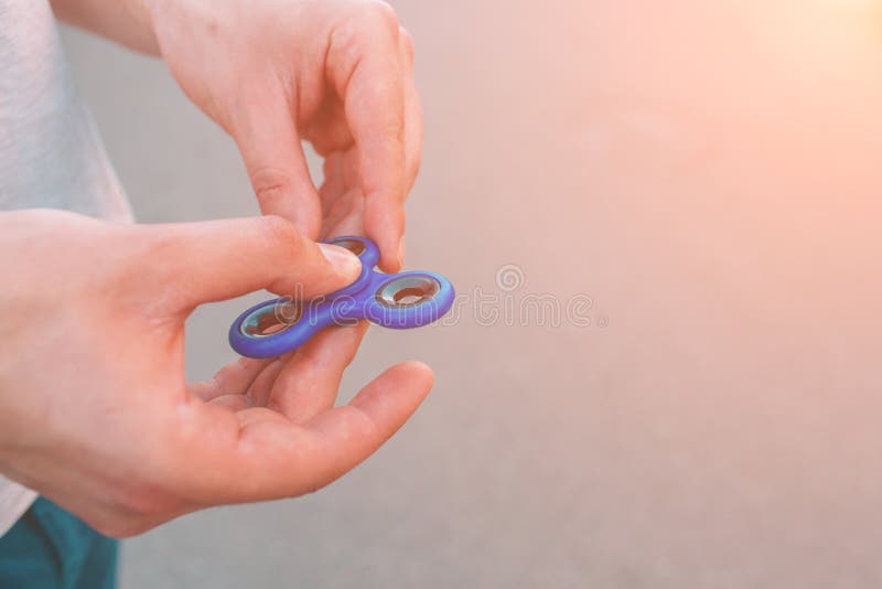 Young Man Holding and Playing with Fidget Spinner. Stock Photo - Image ...