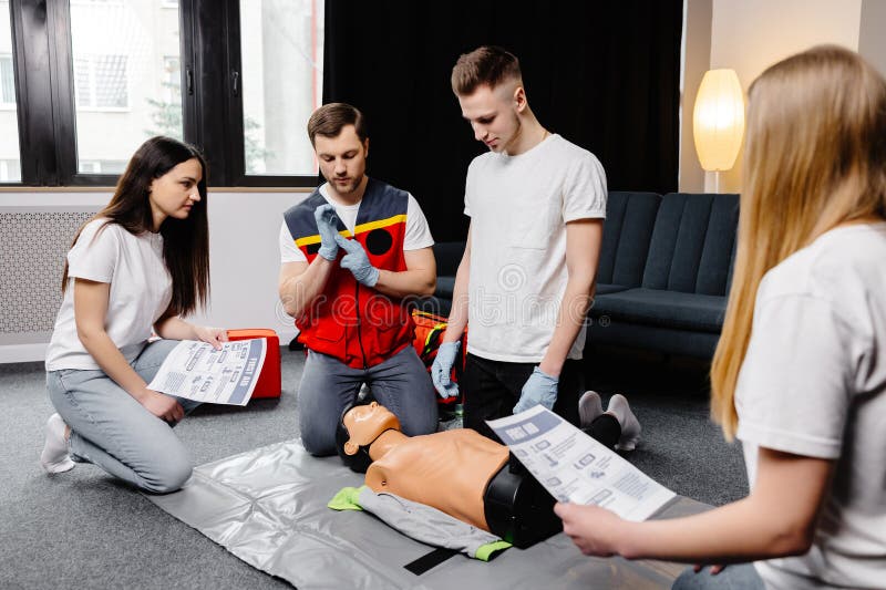Young Man Instructor Helping To Make First Aid Heart Compressions with ...