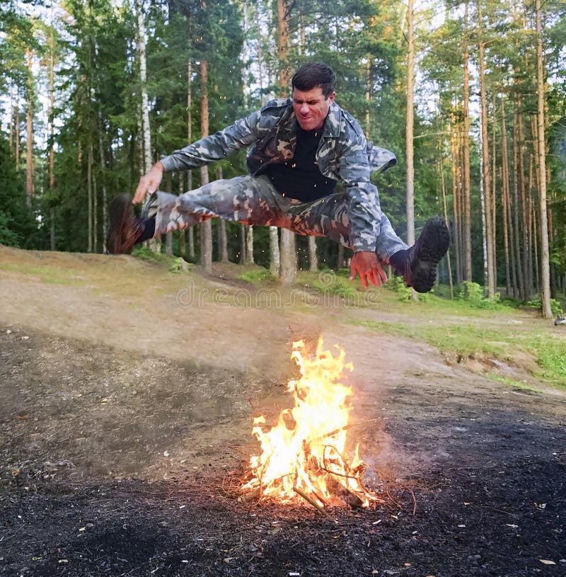 A Young Man in a Jump Over a Burning Fire on the Lake Shore Stock Image ...