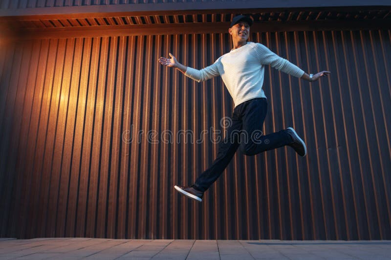 Young Man Jumping with Joy in Modern Urban Setting with Dramatic ...