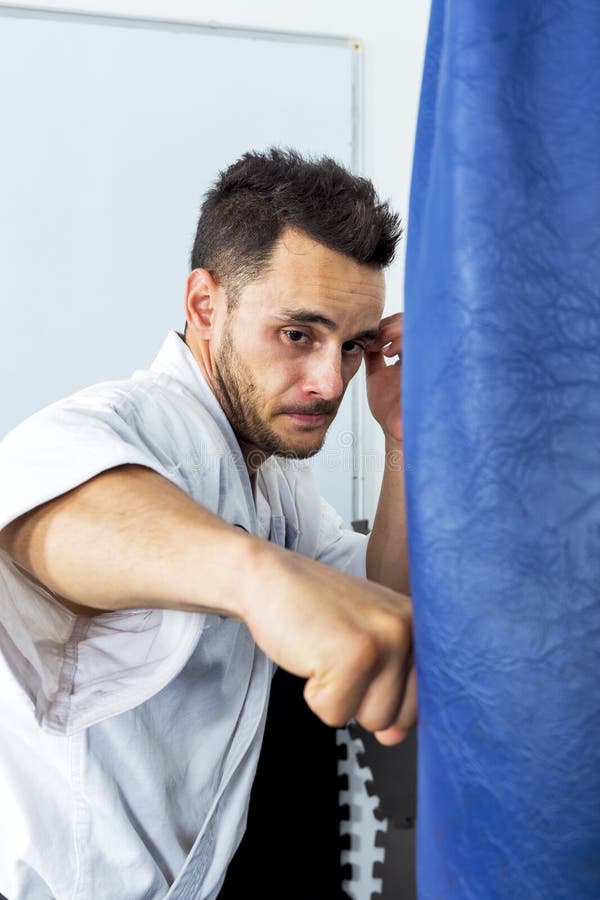 Young Man in Kimono Throwing Punches at a Heavy Punching Bag Stock ...