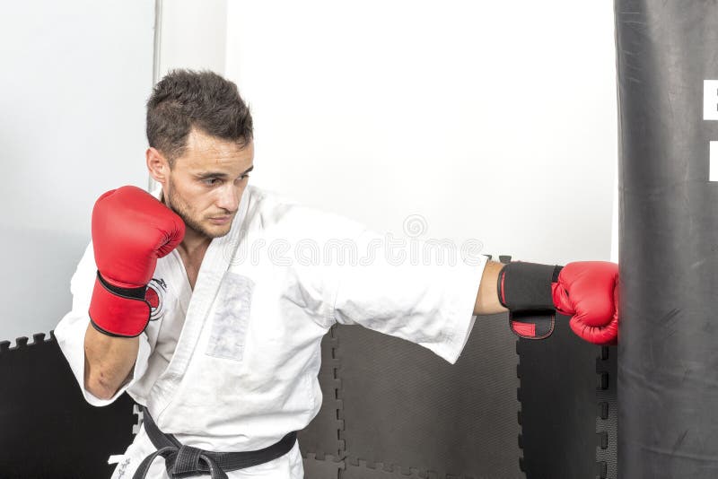 Young Man in Kimono Throwing Punches at a Heavy Punching Bag Stock ...