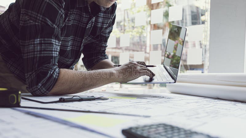 Young Man with a Laptop Plotting a System of Building Structures in ...