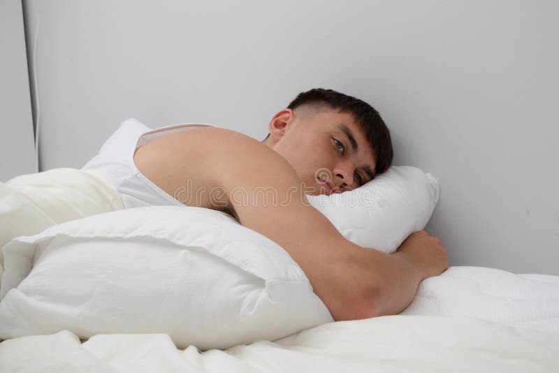 Young man laying in bed stock photo. Image of male, lifestyle - 283769146