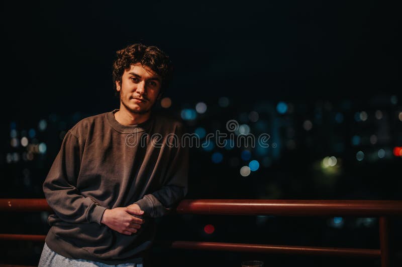 Young Man Leaning on Balcony Railing at Night with City Lights Stock ...