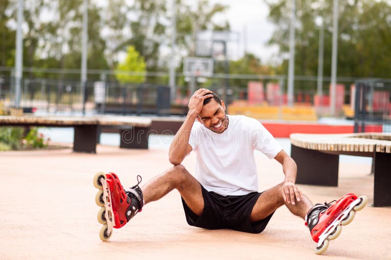 Young Man Learning Riding the Rollers and Laughing while Falling Down ...